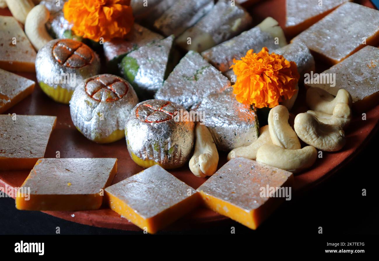 Assorted indian sweets dry fruits marigold flower in a terracotta clay ...