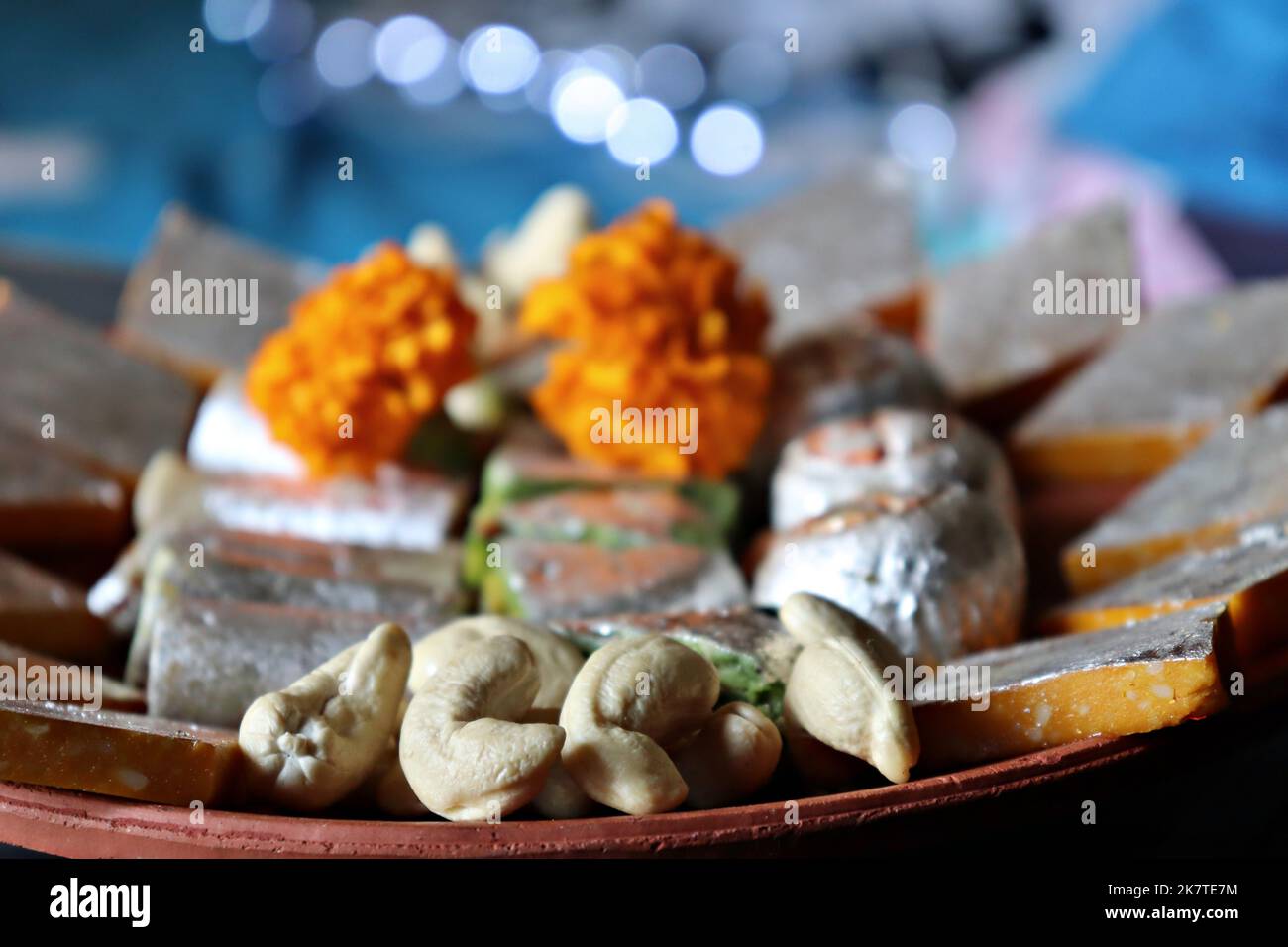 Assorted indian sweets dry fruits marigold flower in a terracotta clay ...