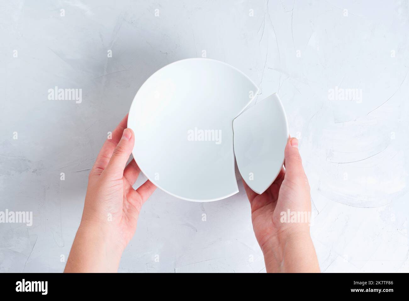 Top view of a broken white bowl in hands on a concrete background Stock ...
