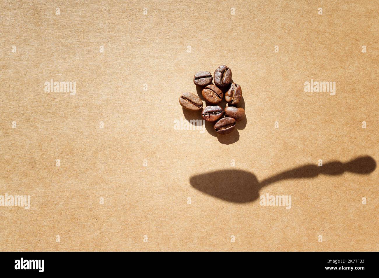 Heap of roasted coffee beans and a spoon shadow silhouette on a craft ...