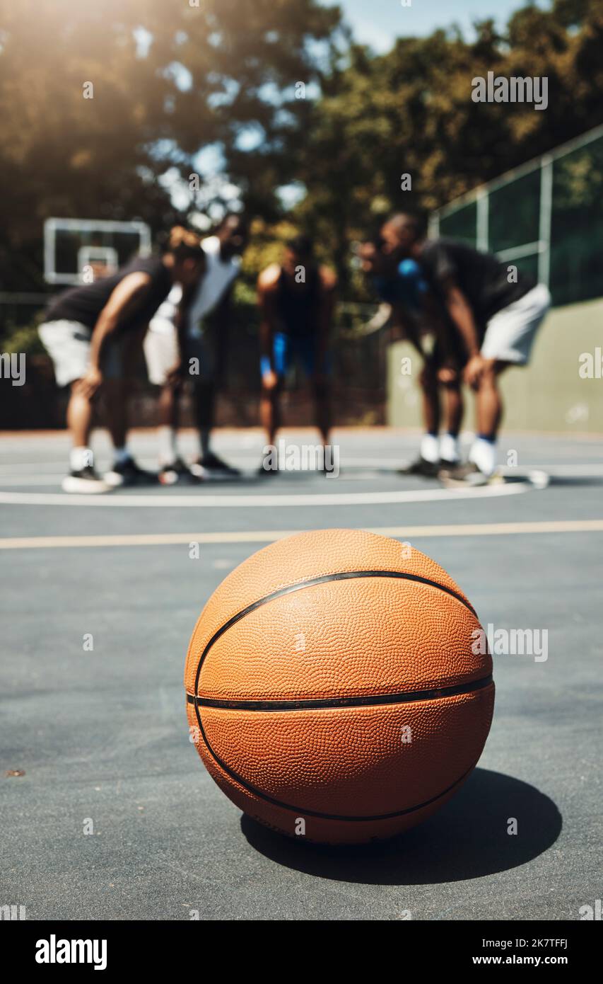 Basketball, ball and outdoor court with athlete group or team talk ...