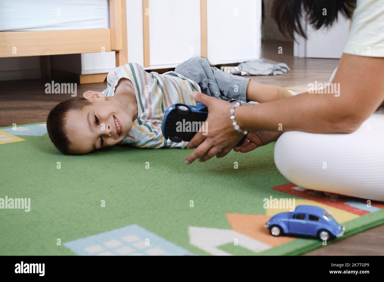 Kid with health problem playing toy cars with mother at home. child ...
