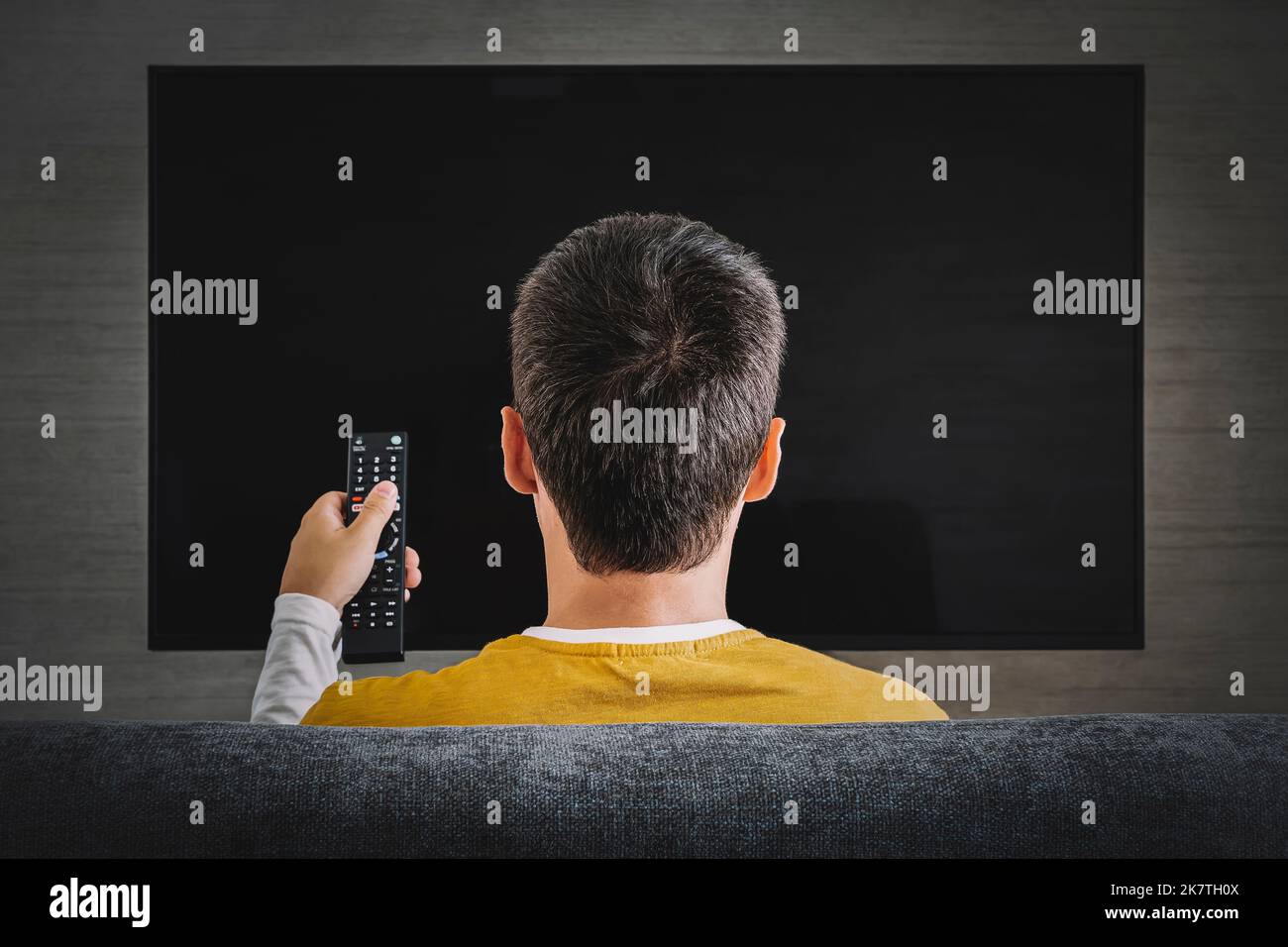 Man watching television, turning on plasma flatscreen TV-set, pointing ...