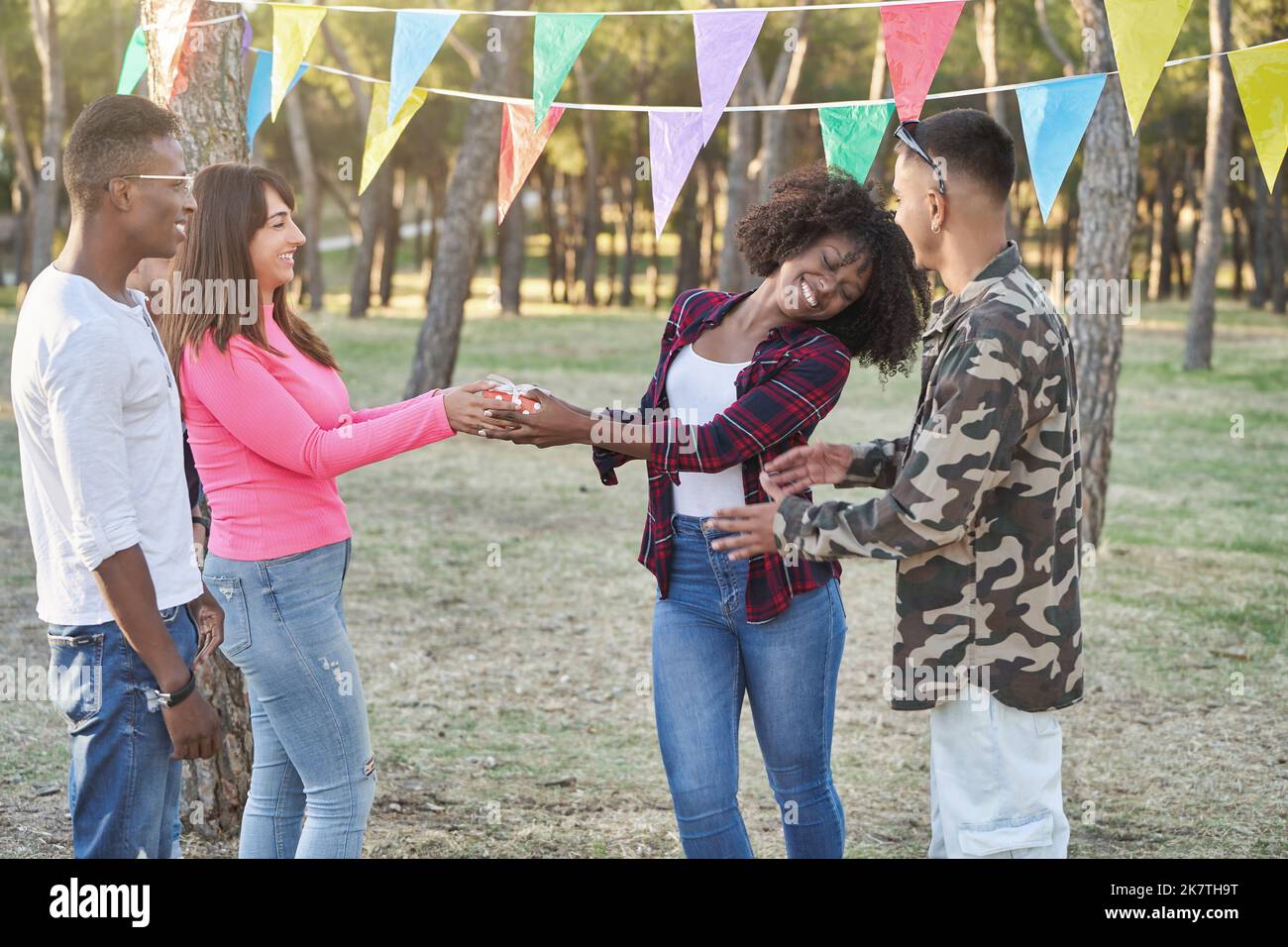 Group of friends giving a birthday present to their friend while having ...