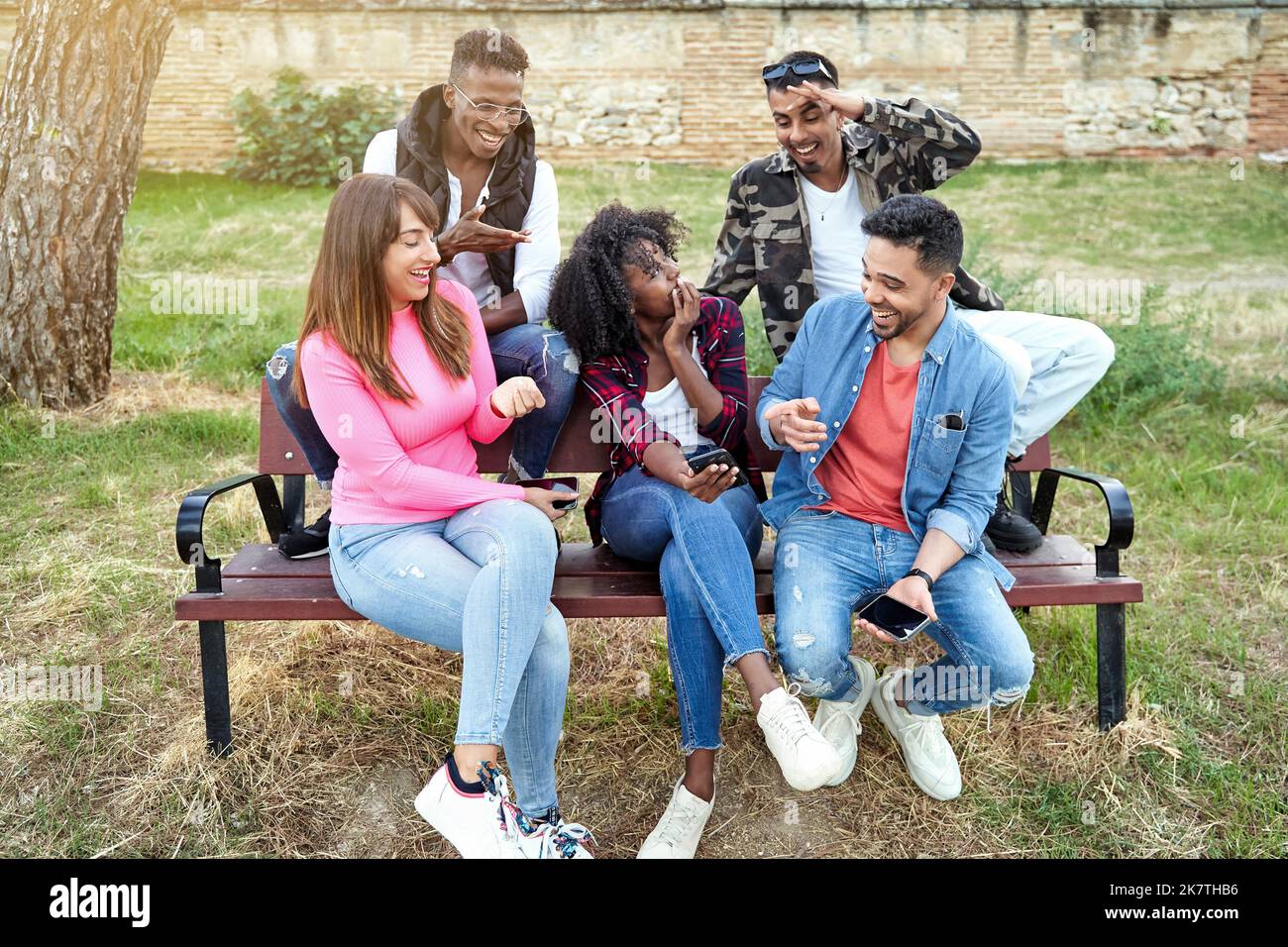 Multi-ethnic friends having fun and laughing while using a mobile phone ...