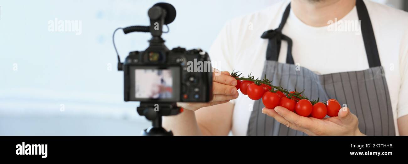 Vlogger chef showing ripe tomatoes ingredient, man in apron recording ...