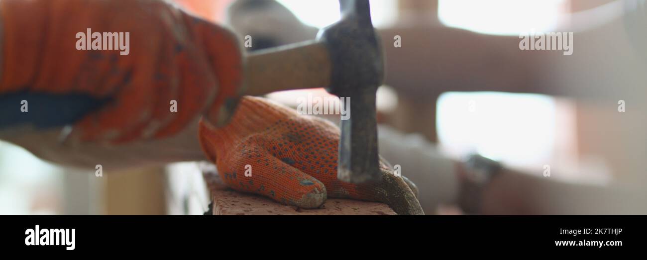 Handyman hammering on red brick with tool, worker wear gloves at work ...