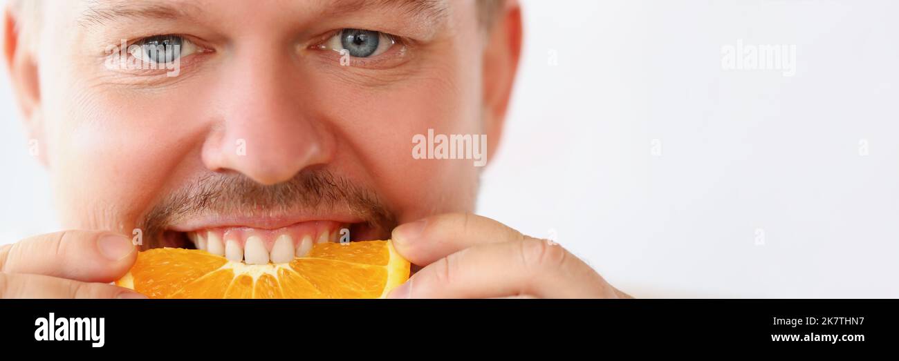 Man bite chopped slice of orange for breakfast in kitchen, healthy ...