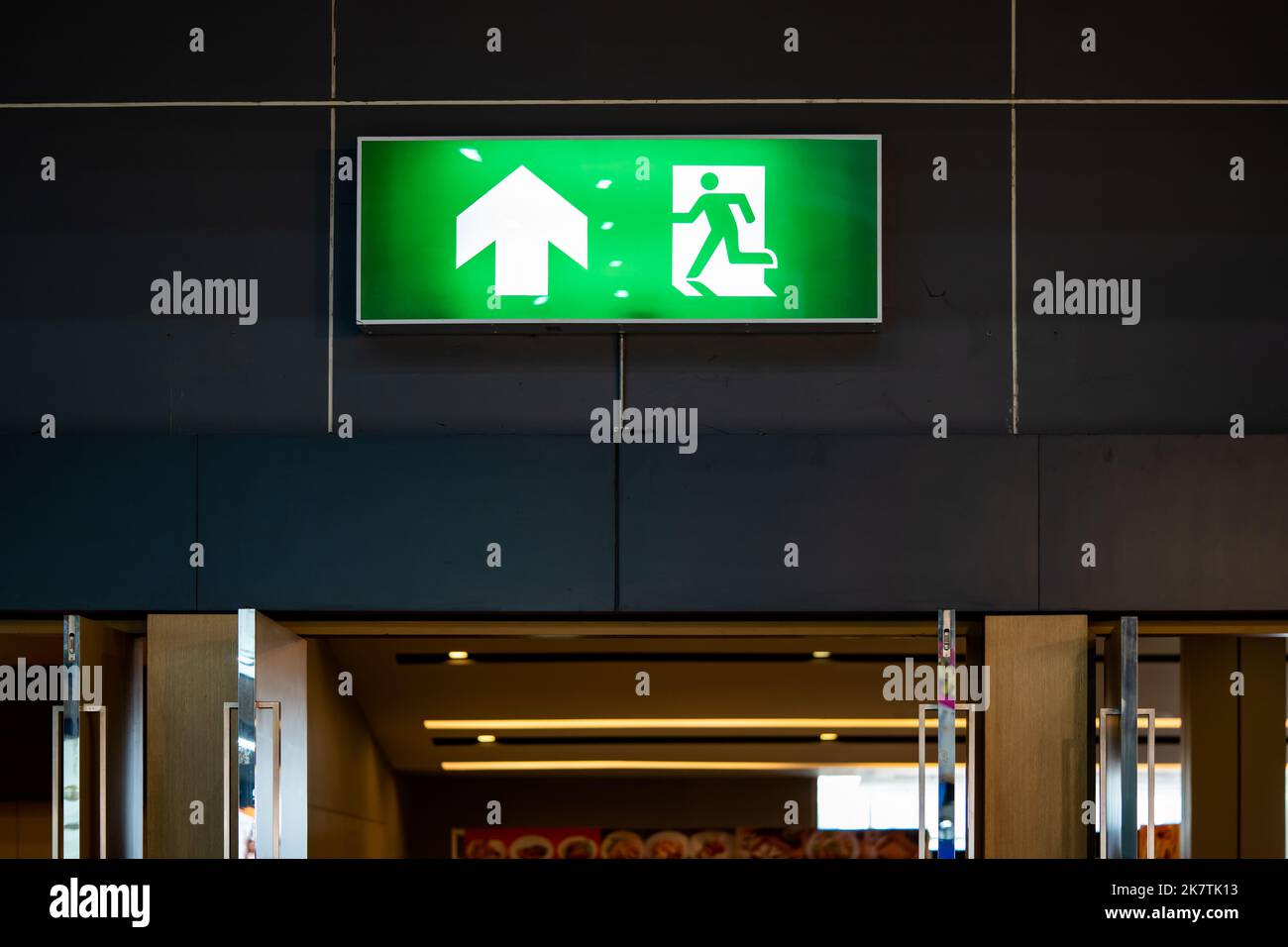 Big Emergency fire exit sign is placed on the black wall over the door ...
