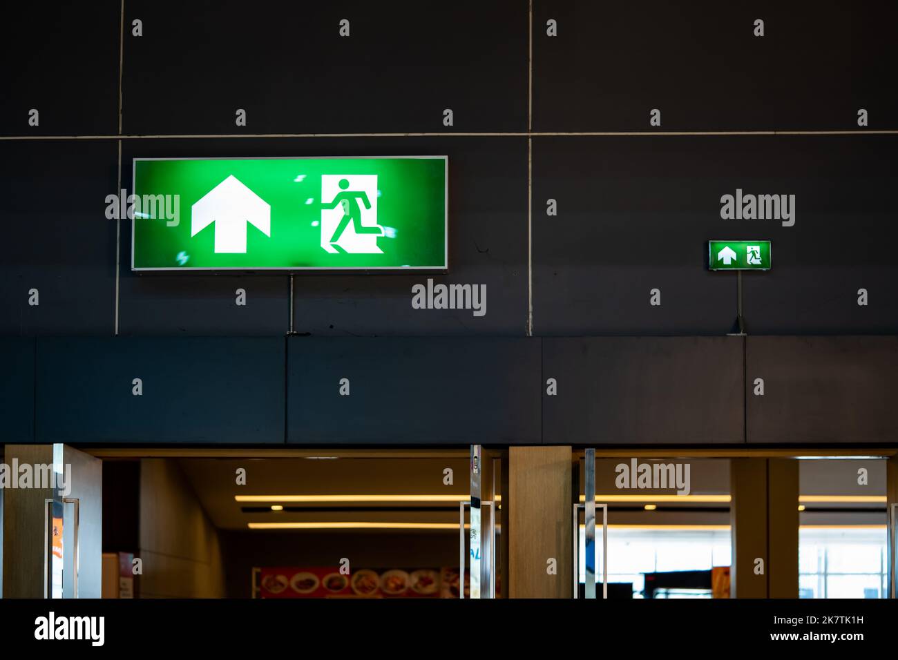 Big Emergency fire exit sign is placed on the black wall over the door ...