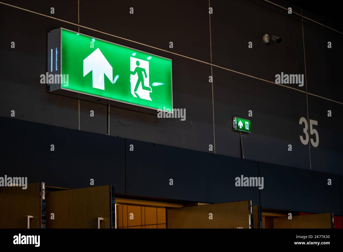 Big Emergency fire exit sign is placed on the black wall over the door ...