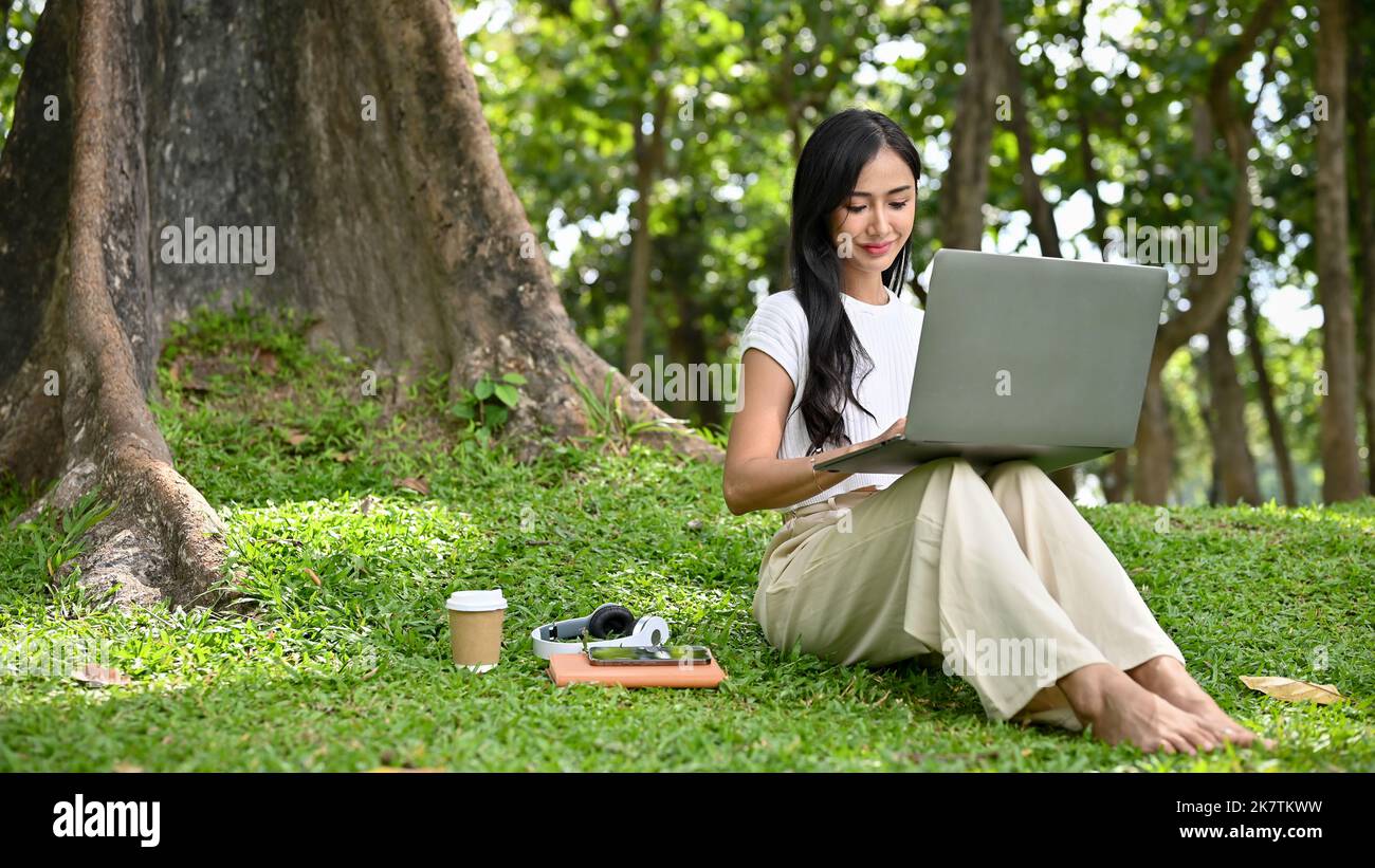 Charming and pretty young Asian female chilling in the city park ...