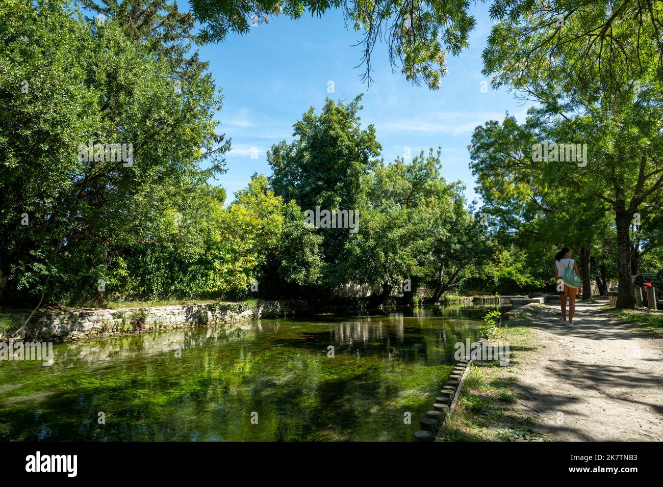 Woman walking near a water canal of L'Isle-sur-la-Sorgue in summer ...
