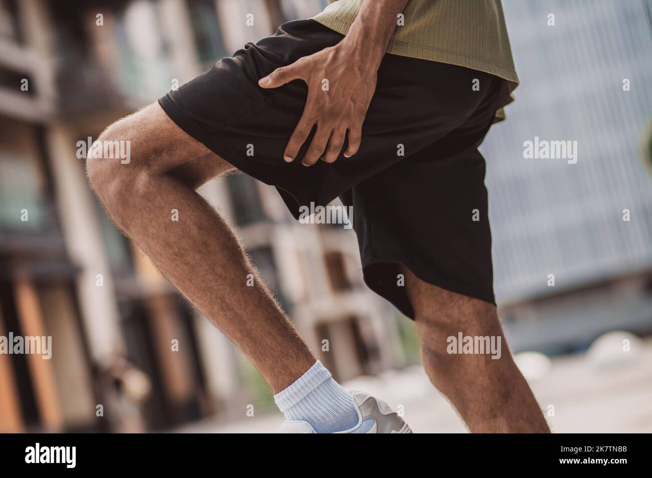 Close up of a man holding his leg in its upper part Stock Photo - Alamy