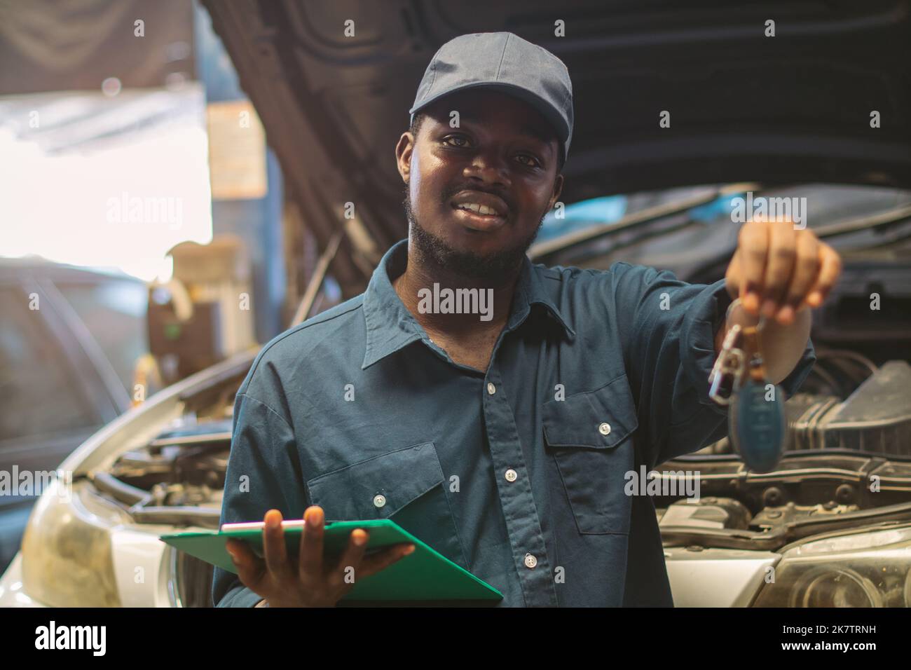 African maintenance male checking car and hands the customer the car ...