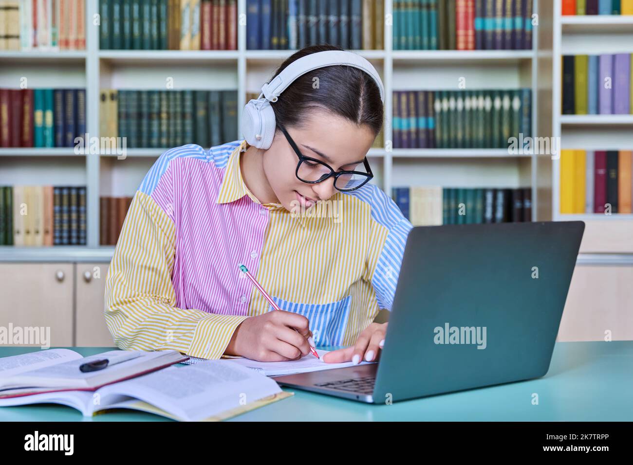 Teenage girl student studying in library, using laptop Stock Photo - Alamy
