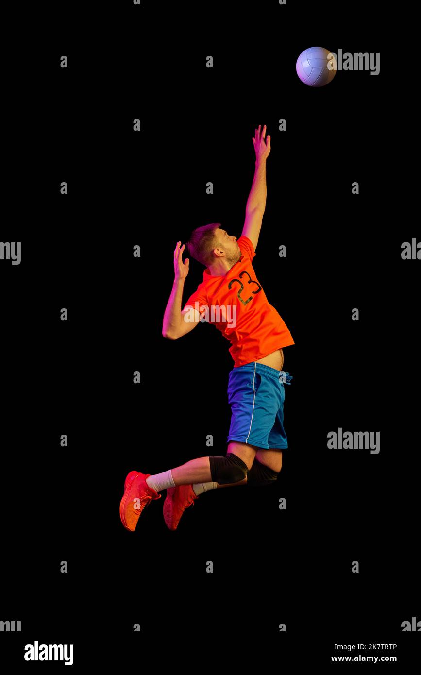 Athlete in motion. Young volleyball player in action isolated on dark ...