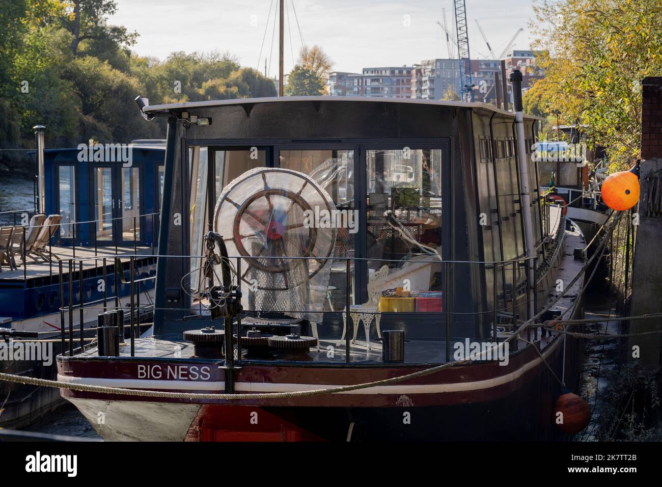 Plastic covers the wheel on the open deck of a houseboat that is moored ...
