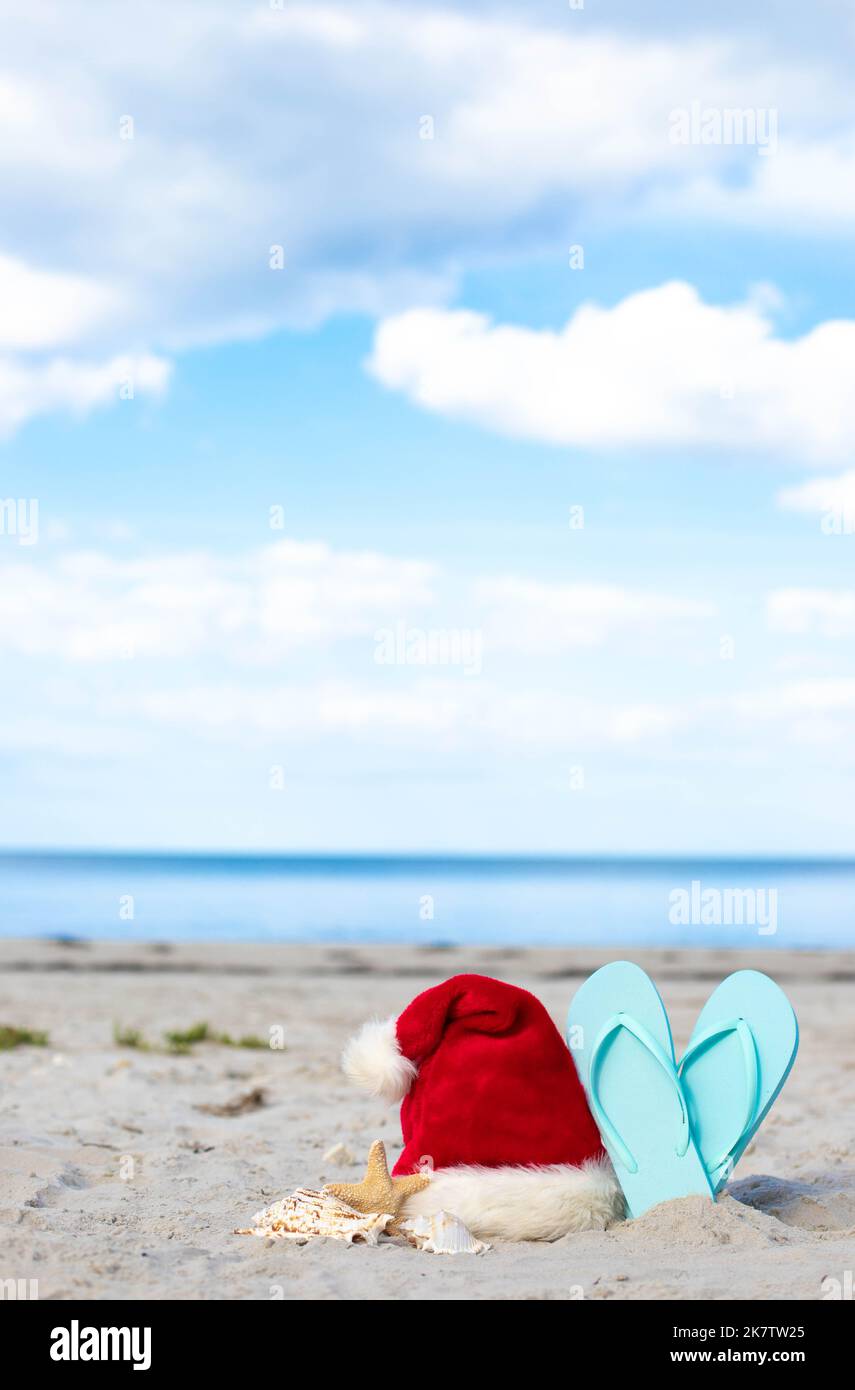 Santa Claus hat and beach sleepers on the beach Stock Photo - Alamy