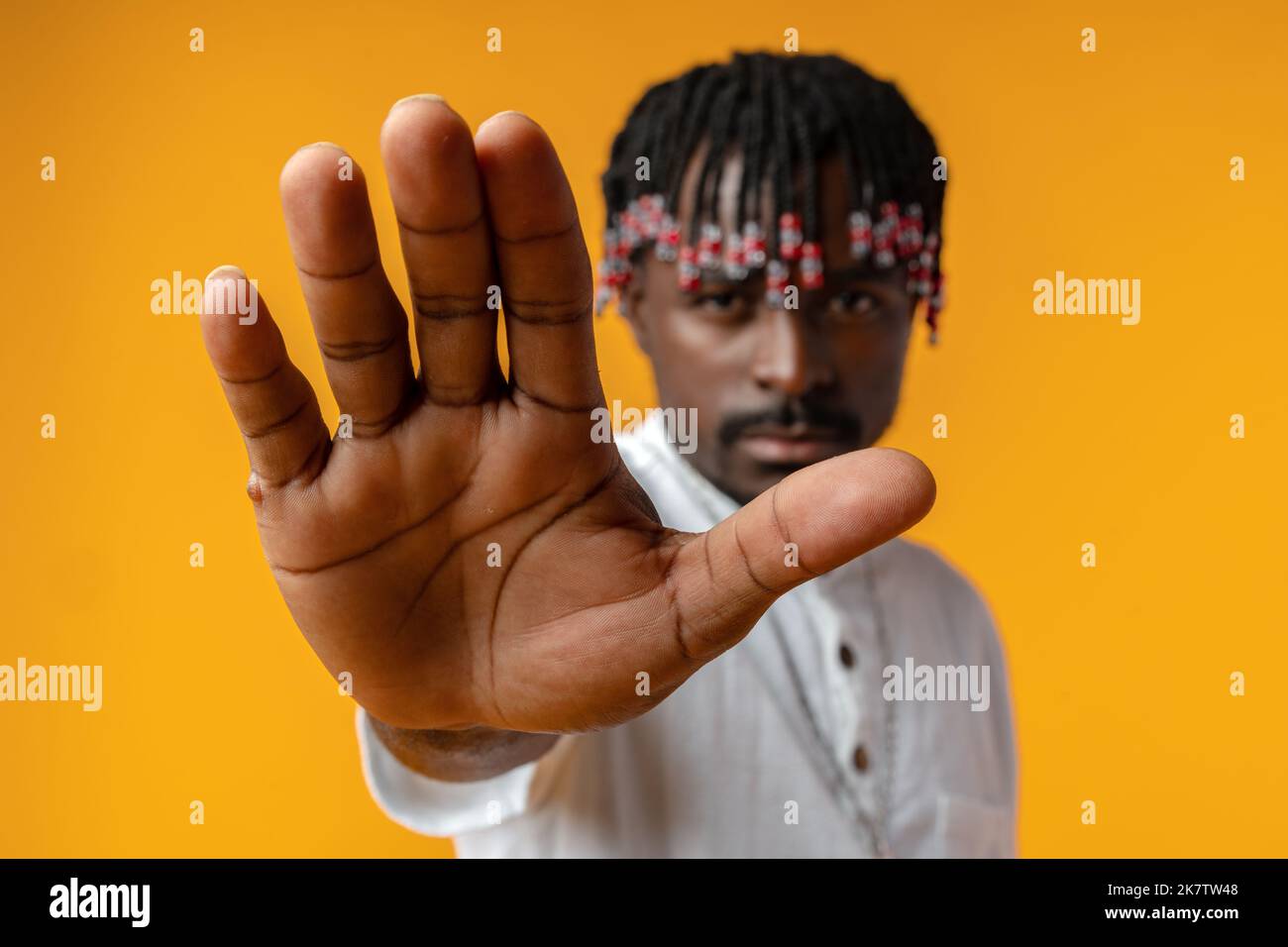 Portrait of serious African male showing hand stop sign on yellow ...