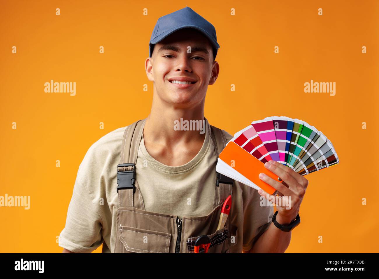 Handsome young worker in uniform holding paint samples palette on ...
