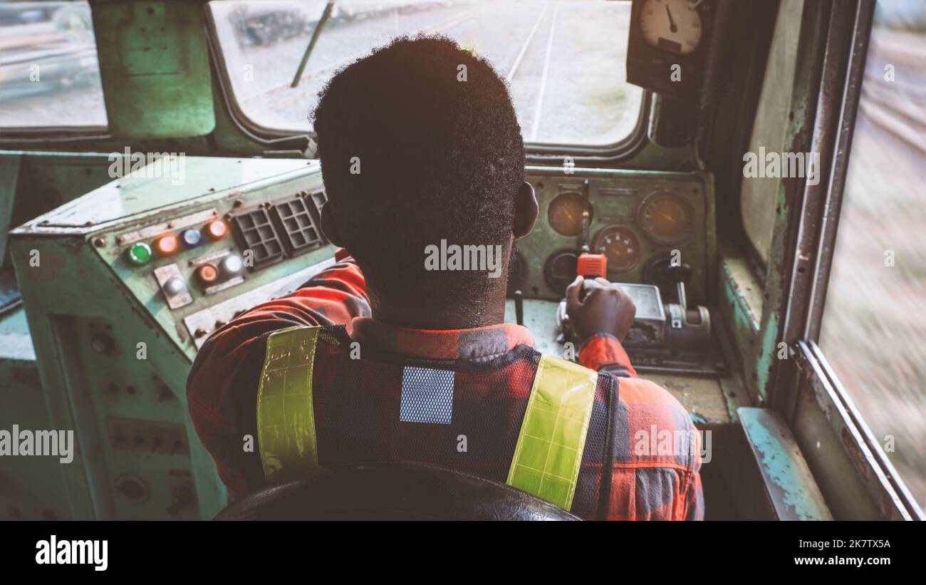 An African train driver is driving a public train on the railway Stock ...
