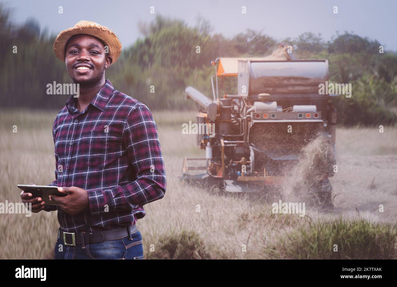 African Farmer holding tablet for combine harvester guidance and ...
