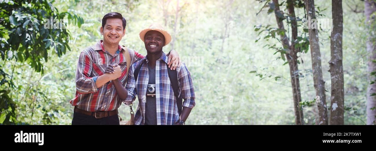 African trekking tourist and his Asian friend hold hands with smiles ...