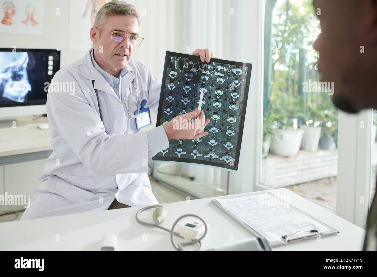 Serious doctor explaining patient why he has to care about spine health ...