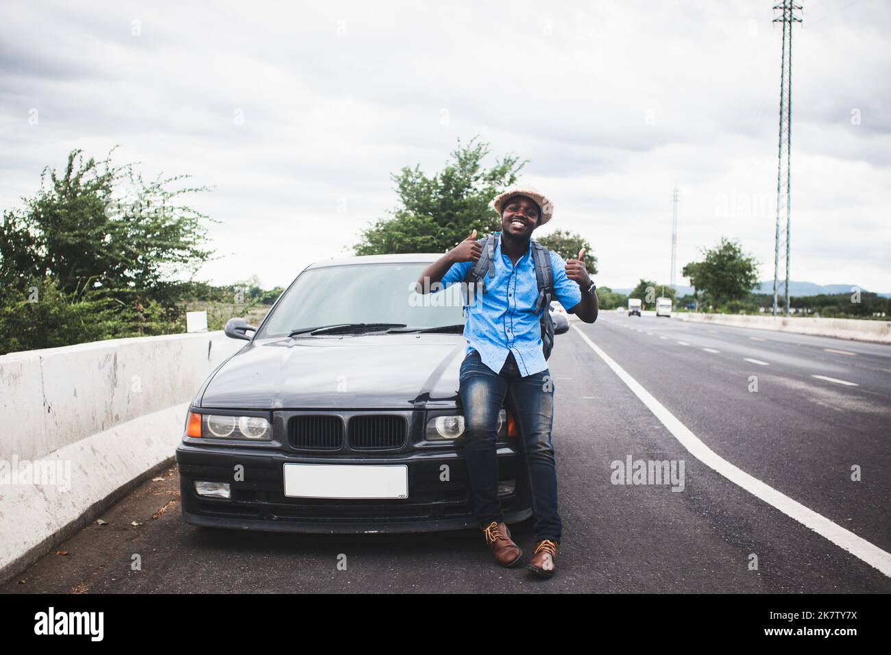 African traveler man stands on car park side off the highway road with ...
