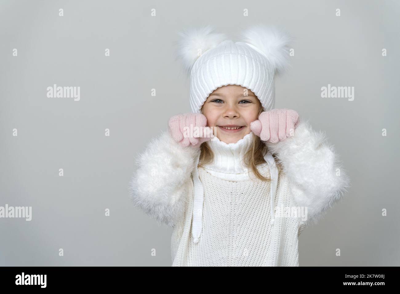 Cute 6 year old girl in a white woolen hat, sweater, gloves and snood ...