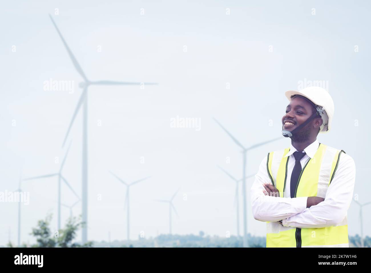 African engineer man stands with smile front the wind turbines ...