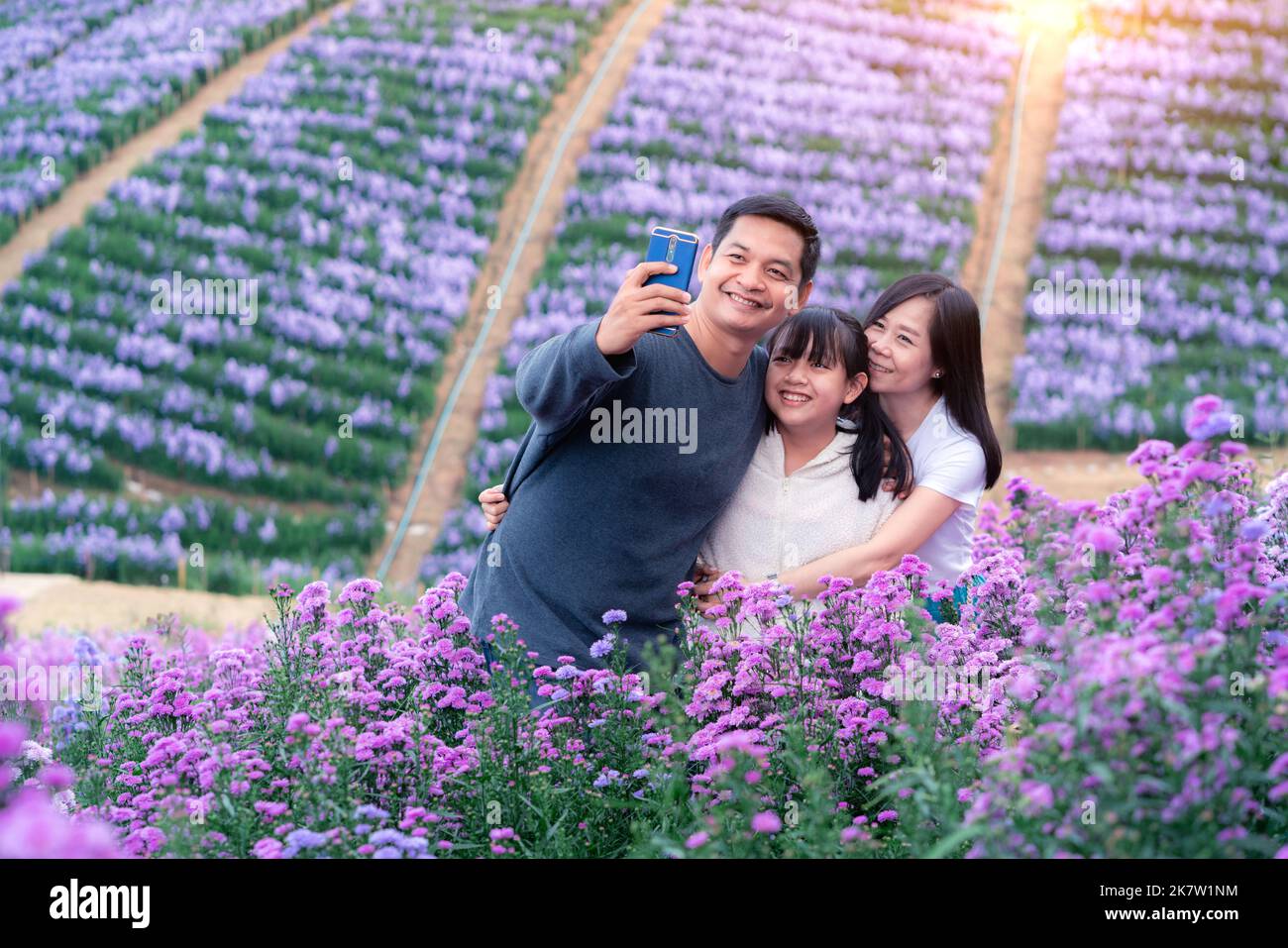 Happy family holding smart phone selfie photo at floral flowers park ...