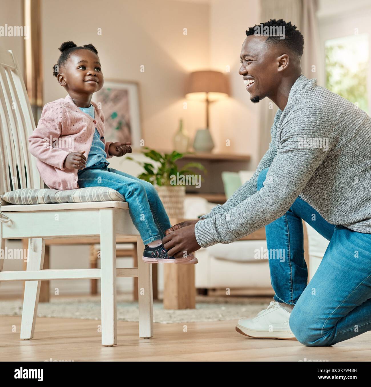 Lemme help you. a handsome young man helping his daughter tie her ...