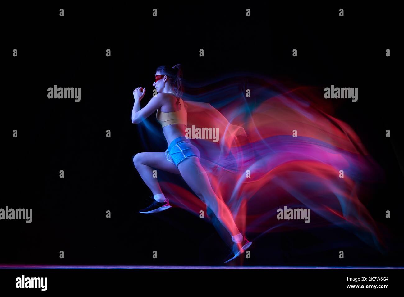 Professional female athlete, runner in motion over dark background in ...