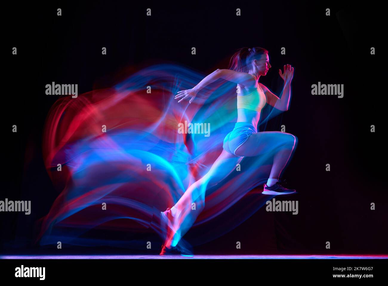 Professional female athlete, runner in motion over dark background in ...