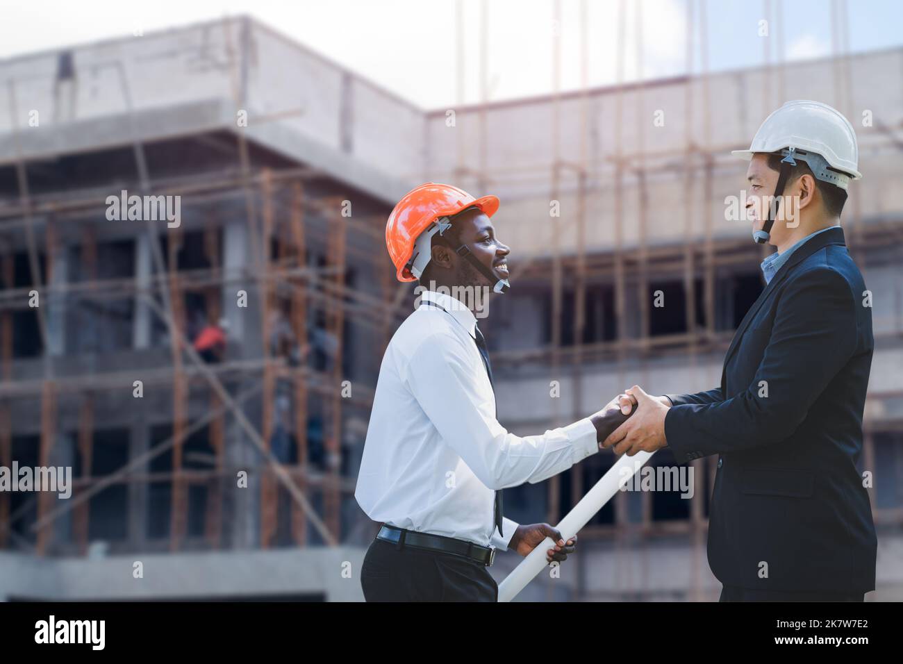 Smiling african engineer and asian construction managers shaking hands ...