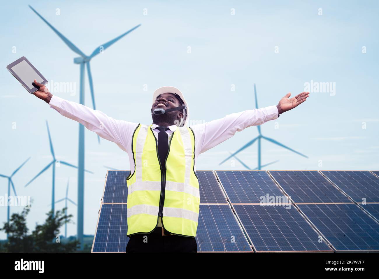 African engineer stand holding tablet front solar photovoltaic and wind ...