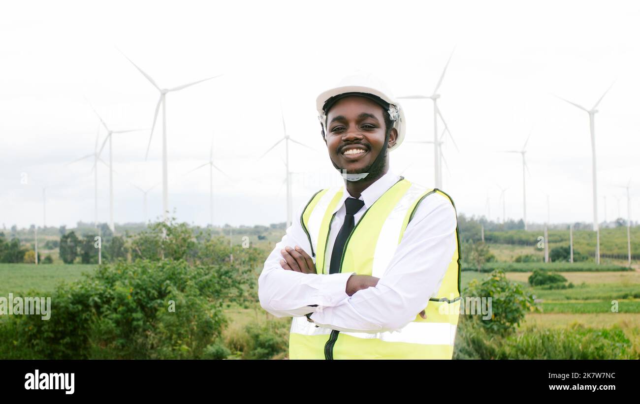 African engineer man stand front wind turbines generating electricity ...