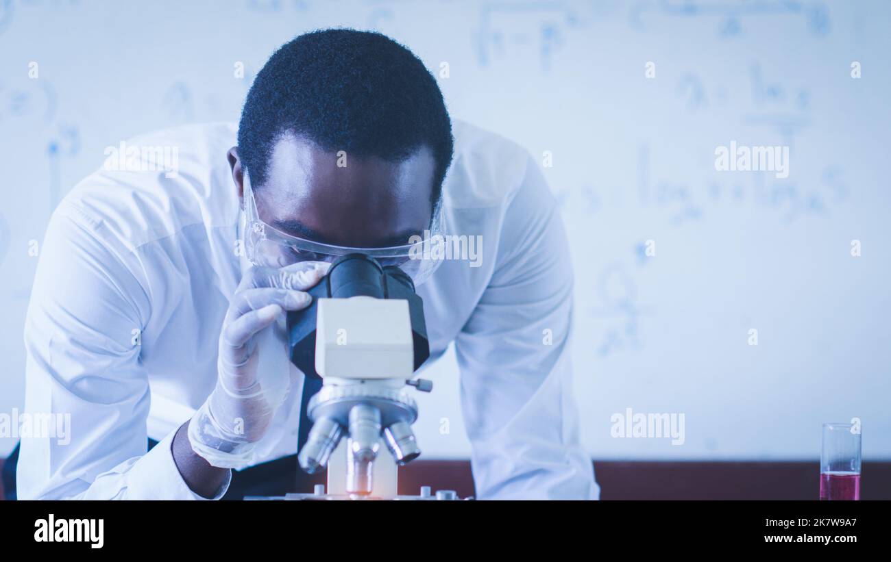 Close-up of african male scientific researcher using microscope in the ...