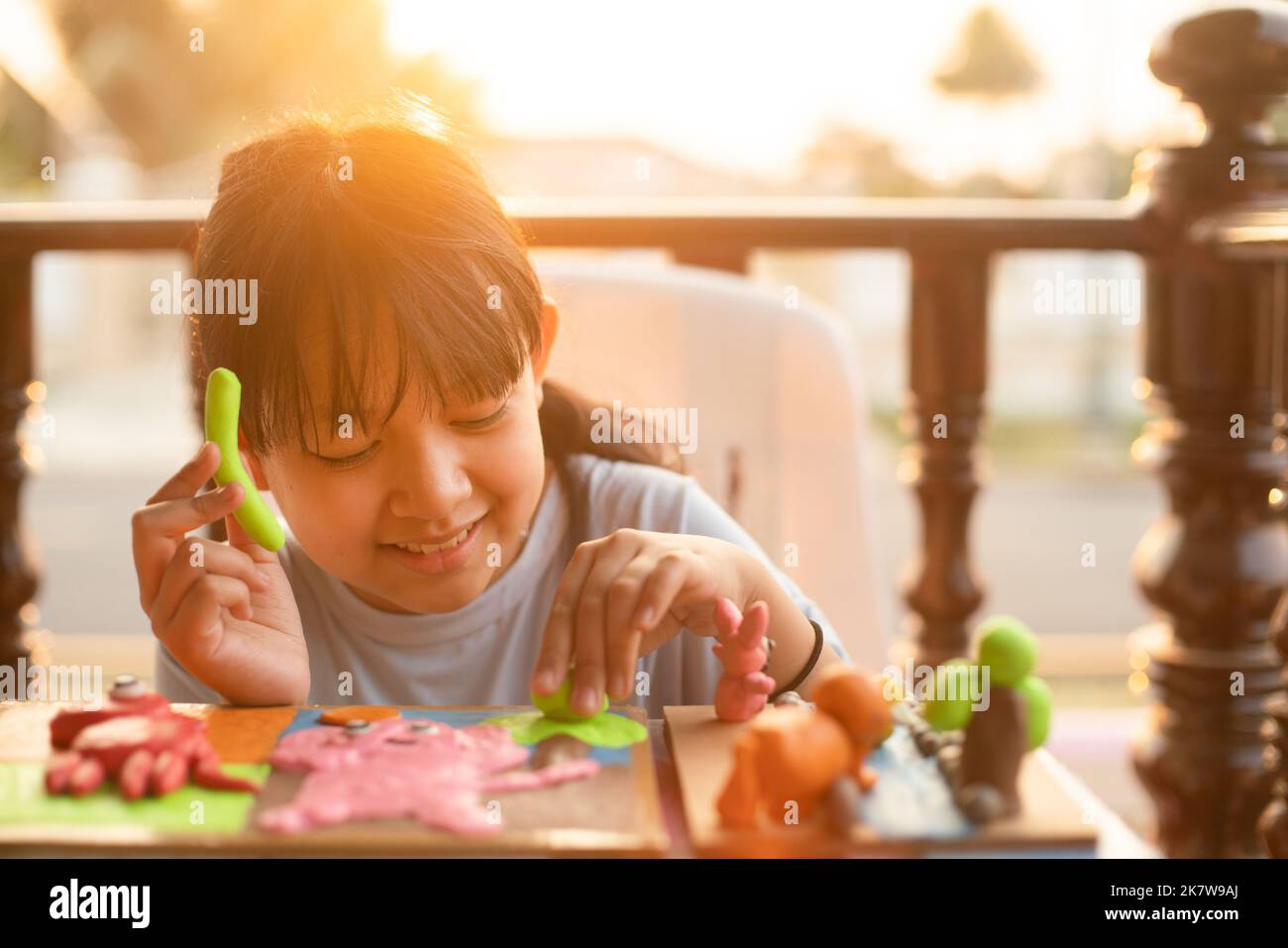 Asian young girl sits happily making plasticine in the house during the ...