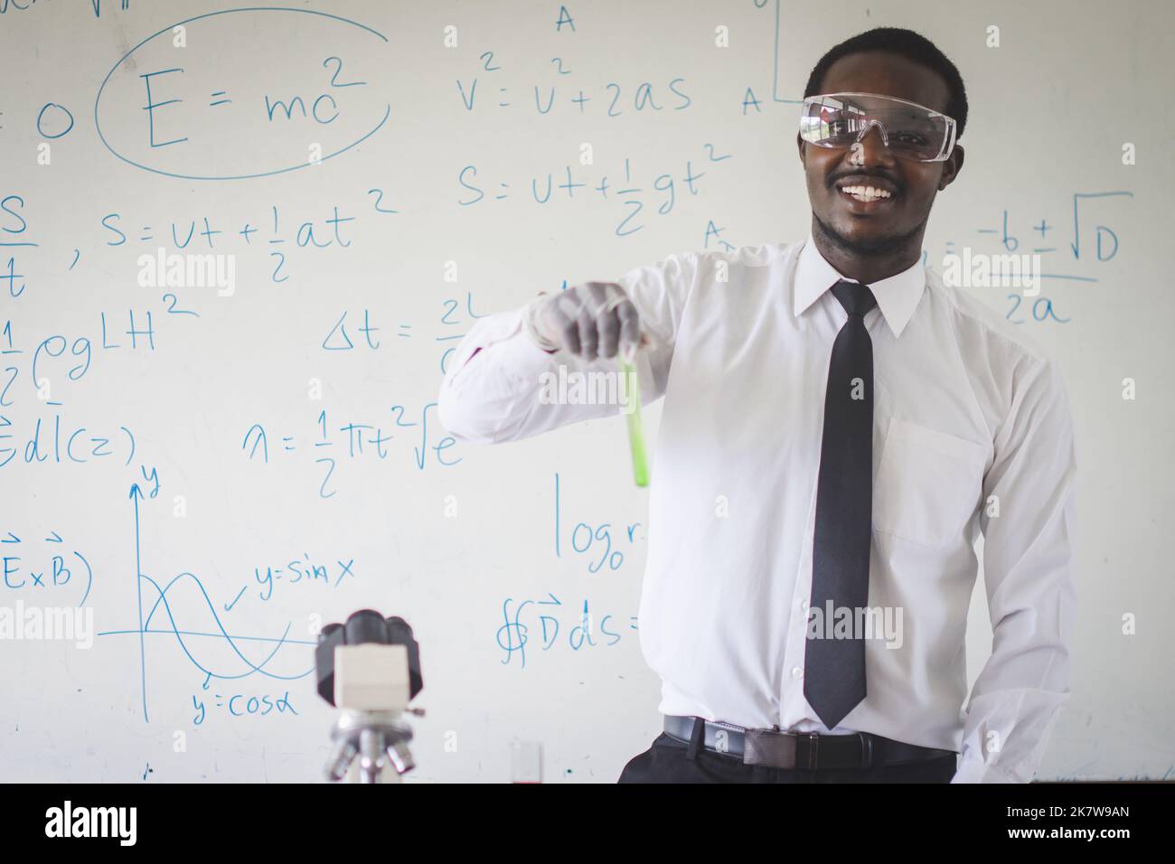 African science teacher conducting experiment mixing liquids in flask ...
