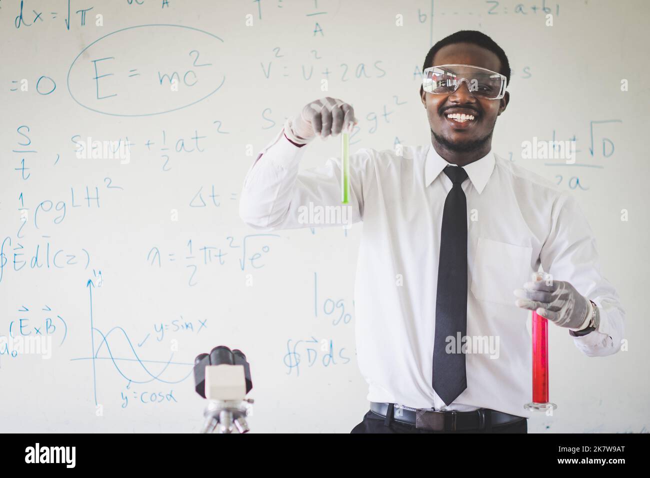 African science teacher conducting experiment mixing liquids in flask ...