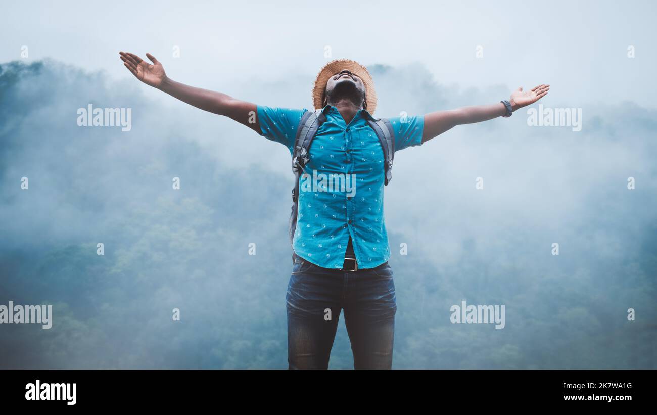 Freedom african traveler man carrying a backpack stands at the top of a ...