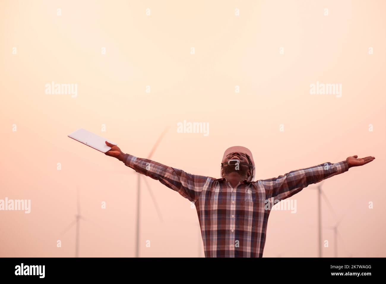 Success african engineer man stands holding tablet front the wind ...