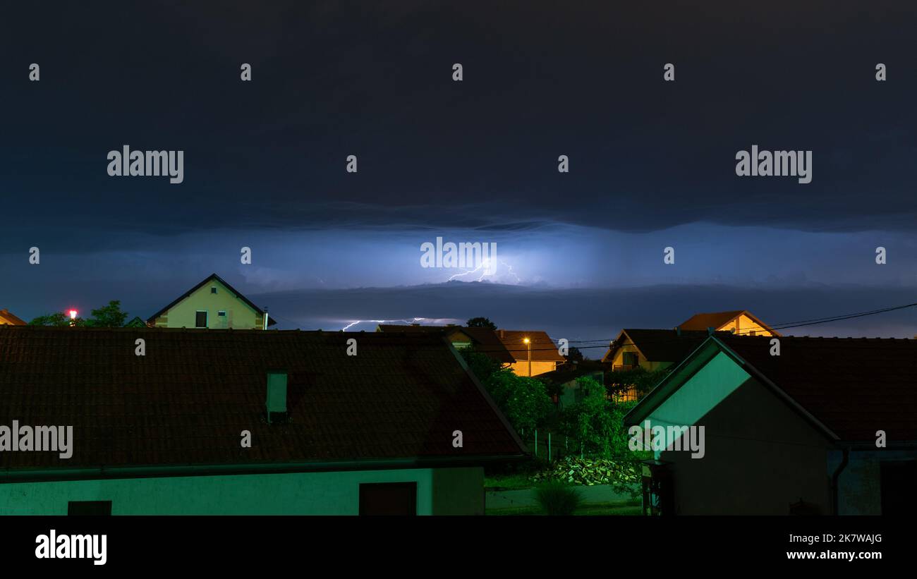 Lightning glow in clouds above suburbs at night, thunderstorm at night ...