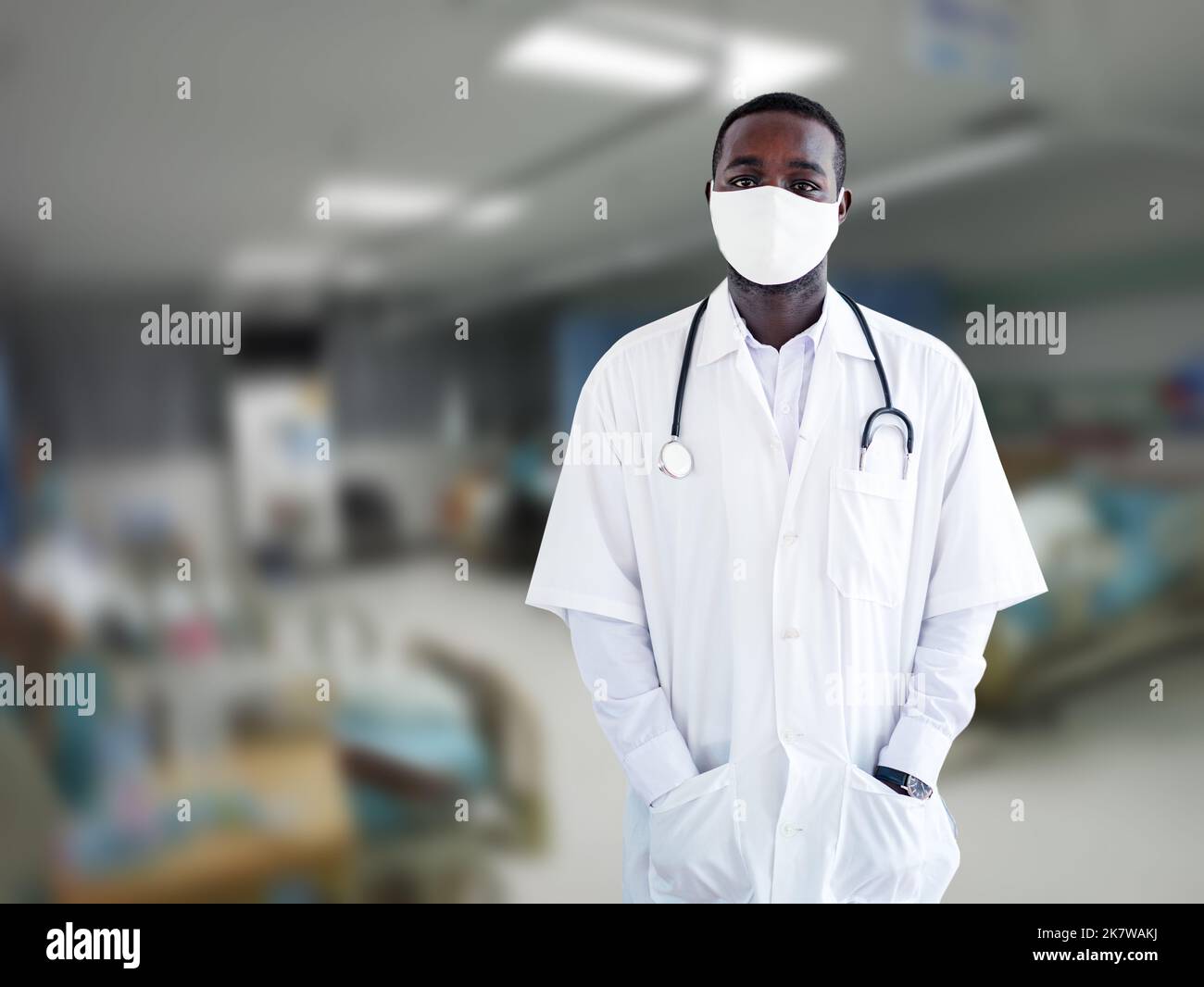 African Doctor stand pose in front of patient lay on bed behind with ...