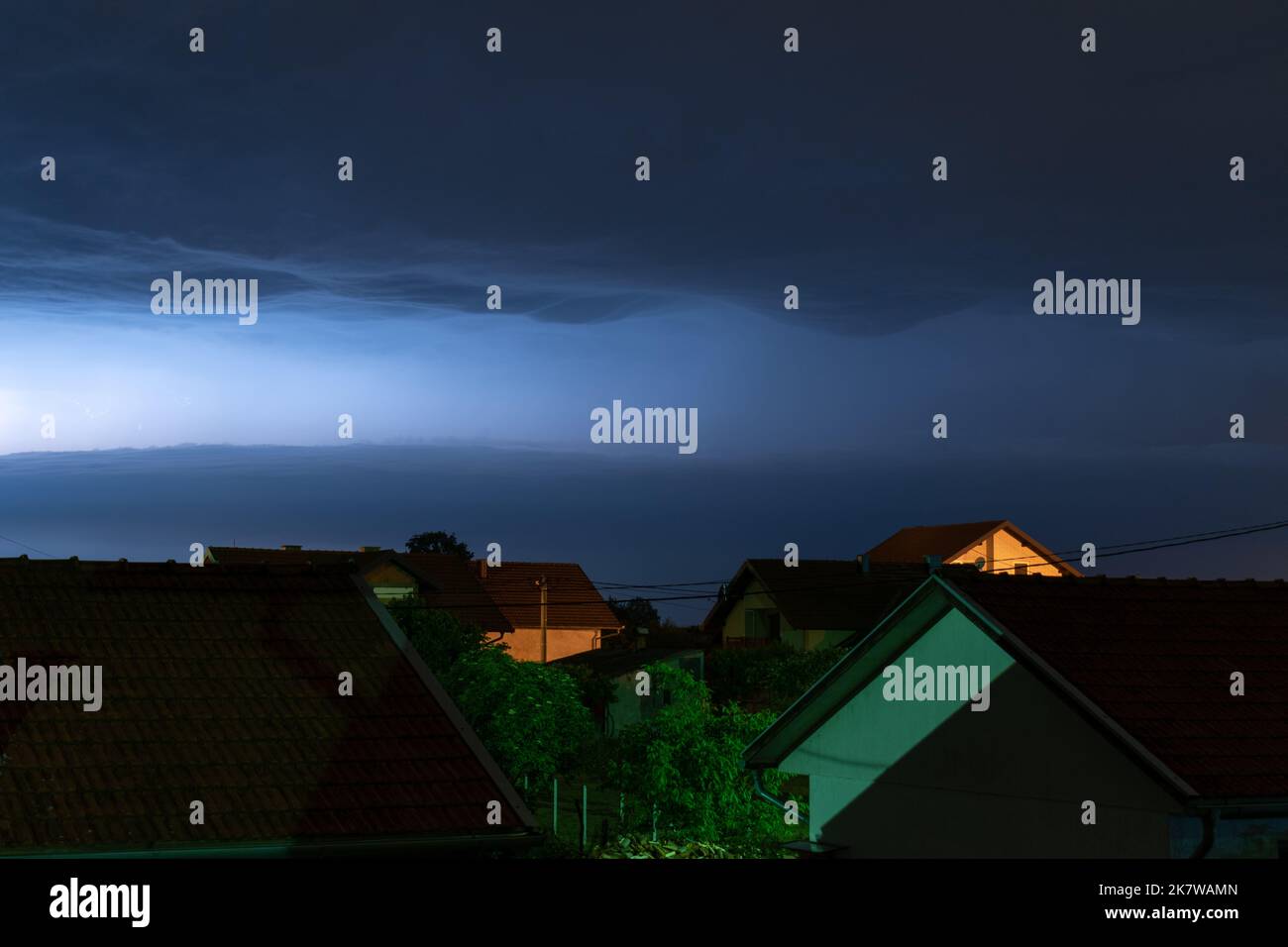 Lightning glow in clouds above suburbs at night, thunderstorm at night ...