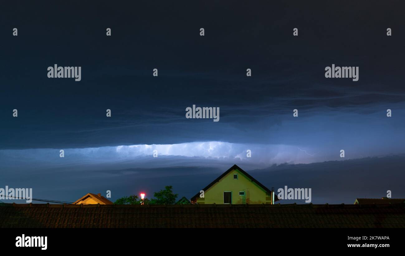Lightning glow in clouds above suburbs at night, thunderstorm at night ...