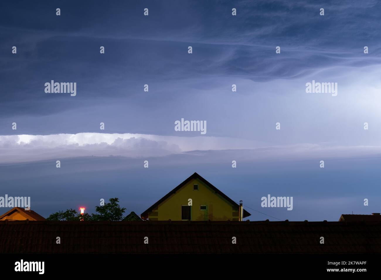 Lightning glow in clouds above suburbs at night, thunderstorm at night ...